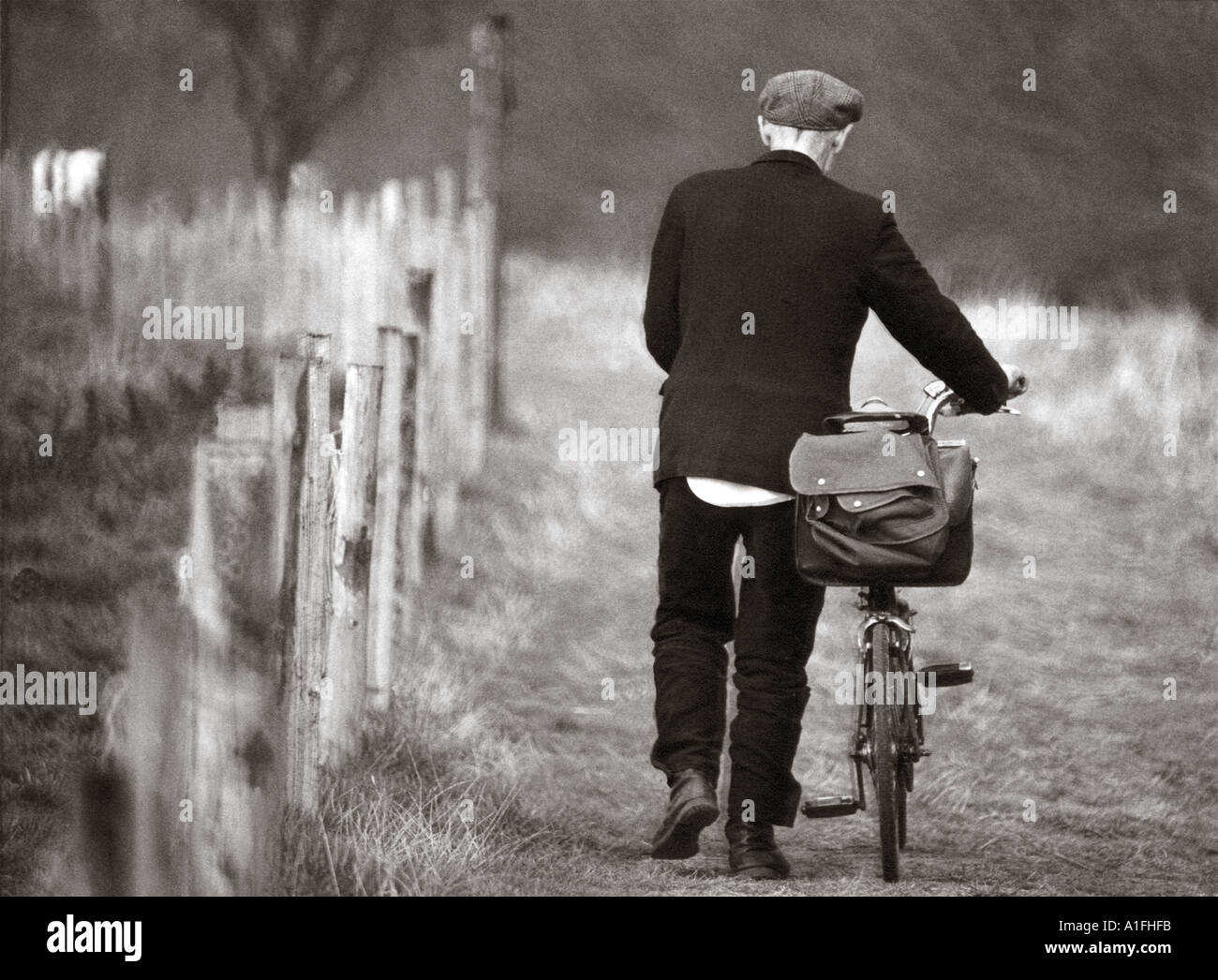 Old man wheeling bike away from camera along country path with ...