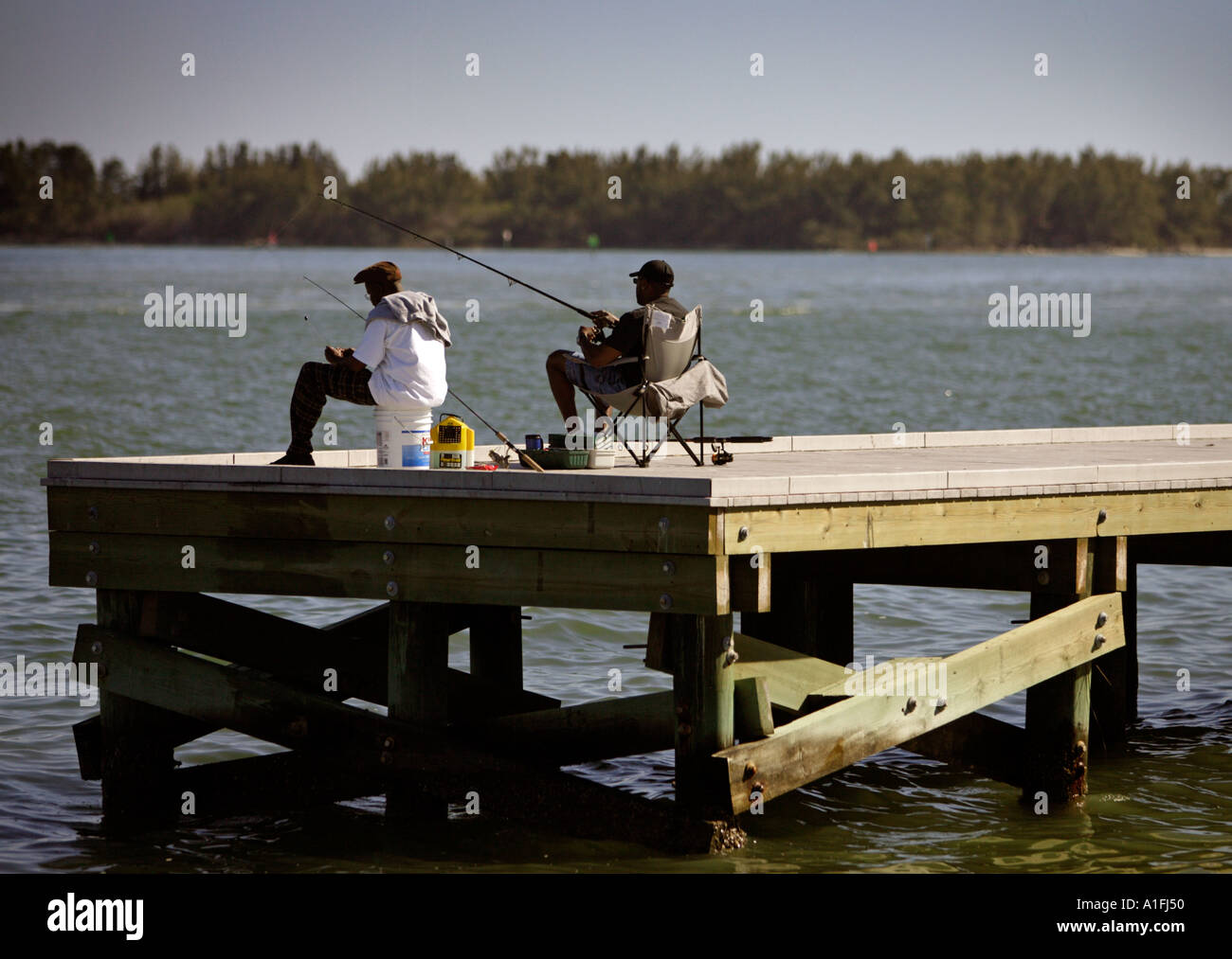 Two men fishing on a pier Stock Photo - Alamy