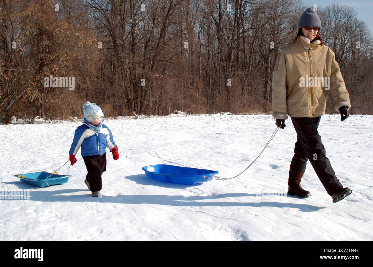 Mother and child pulling sleds Stock Photo - Alamy