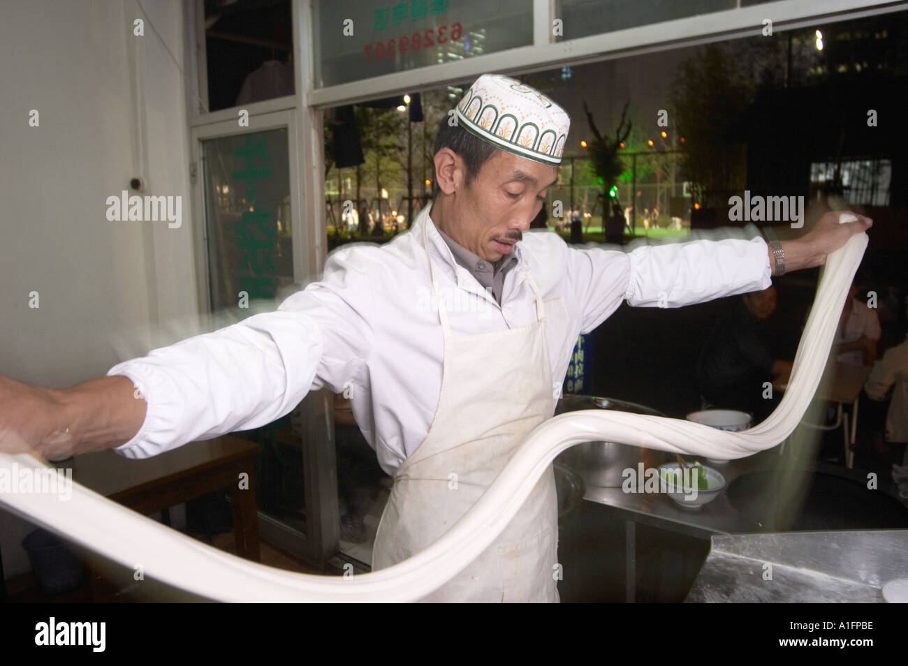 chinese chef making noodles in a simple street side noodle shop in ...