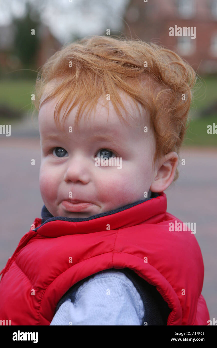 Baby with red hair wearing a red body warmer playing outside Looking ...