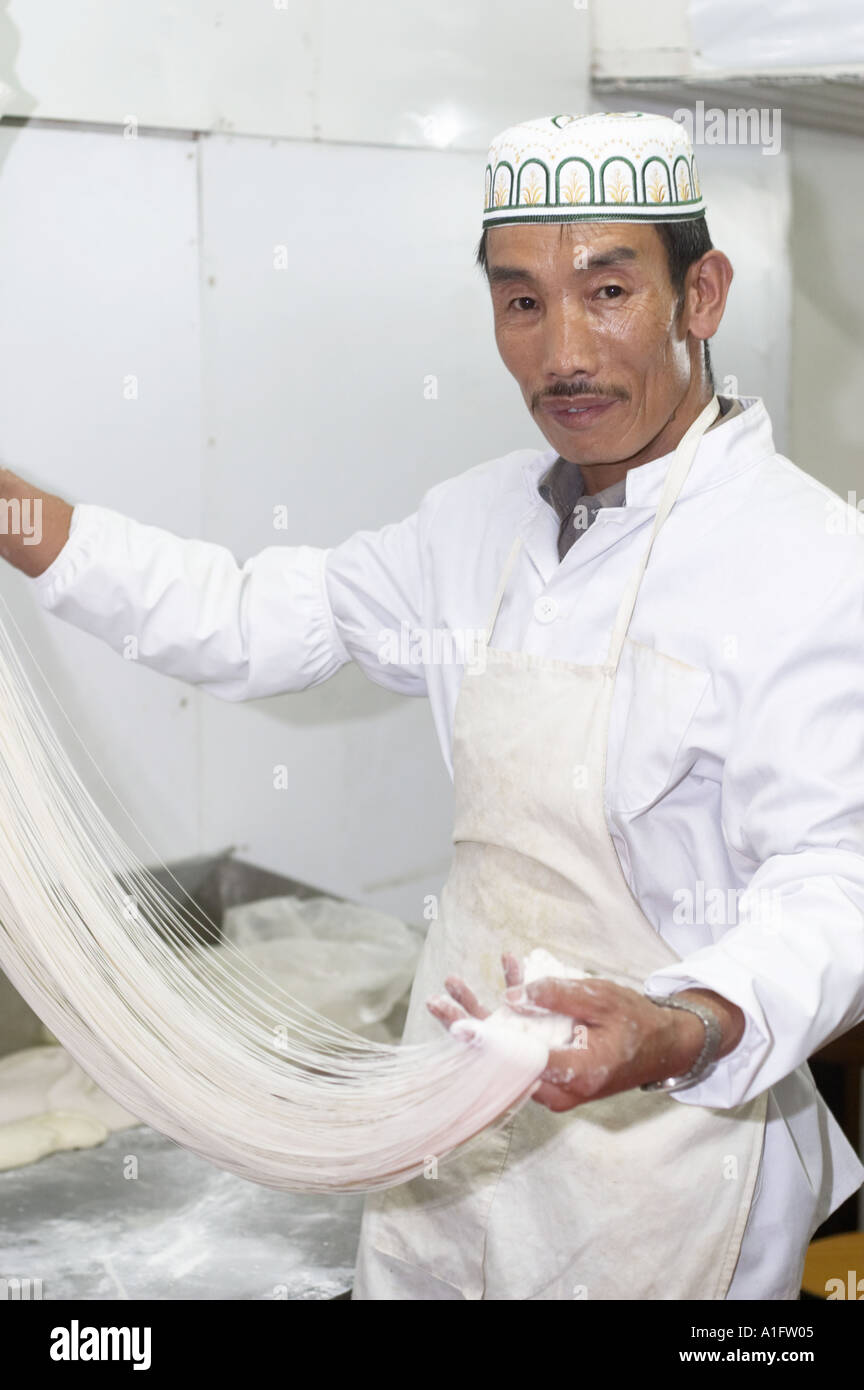 chinese chef making noodles in a simple street side noodle shop in ...