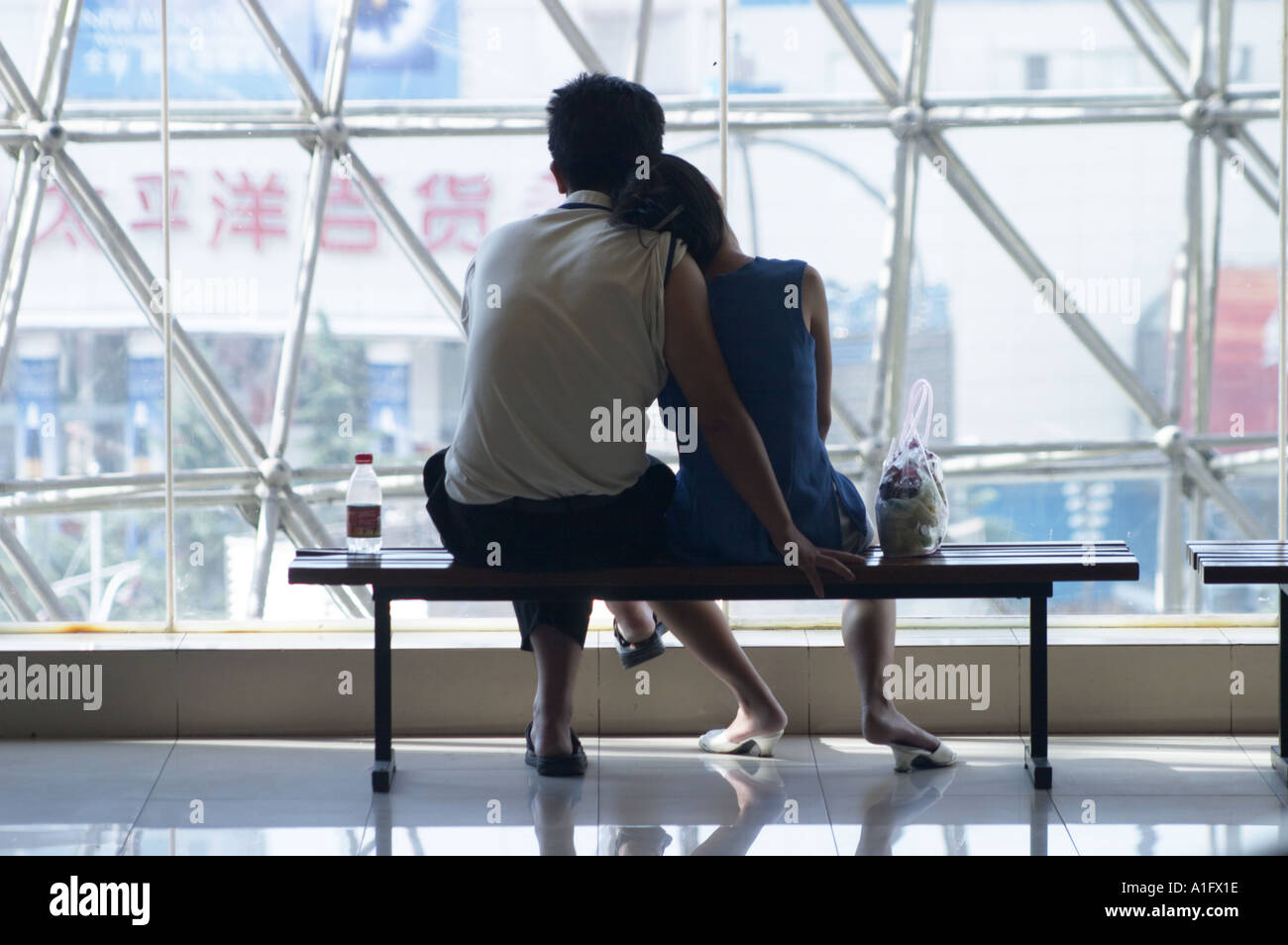 young chinese lovers in love showing affection on bench in sihuette in ...