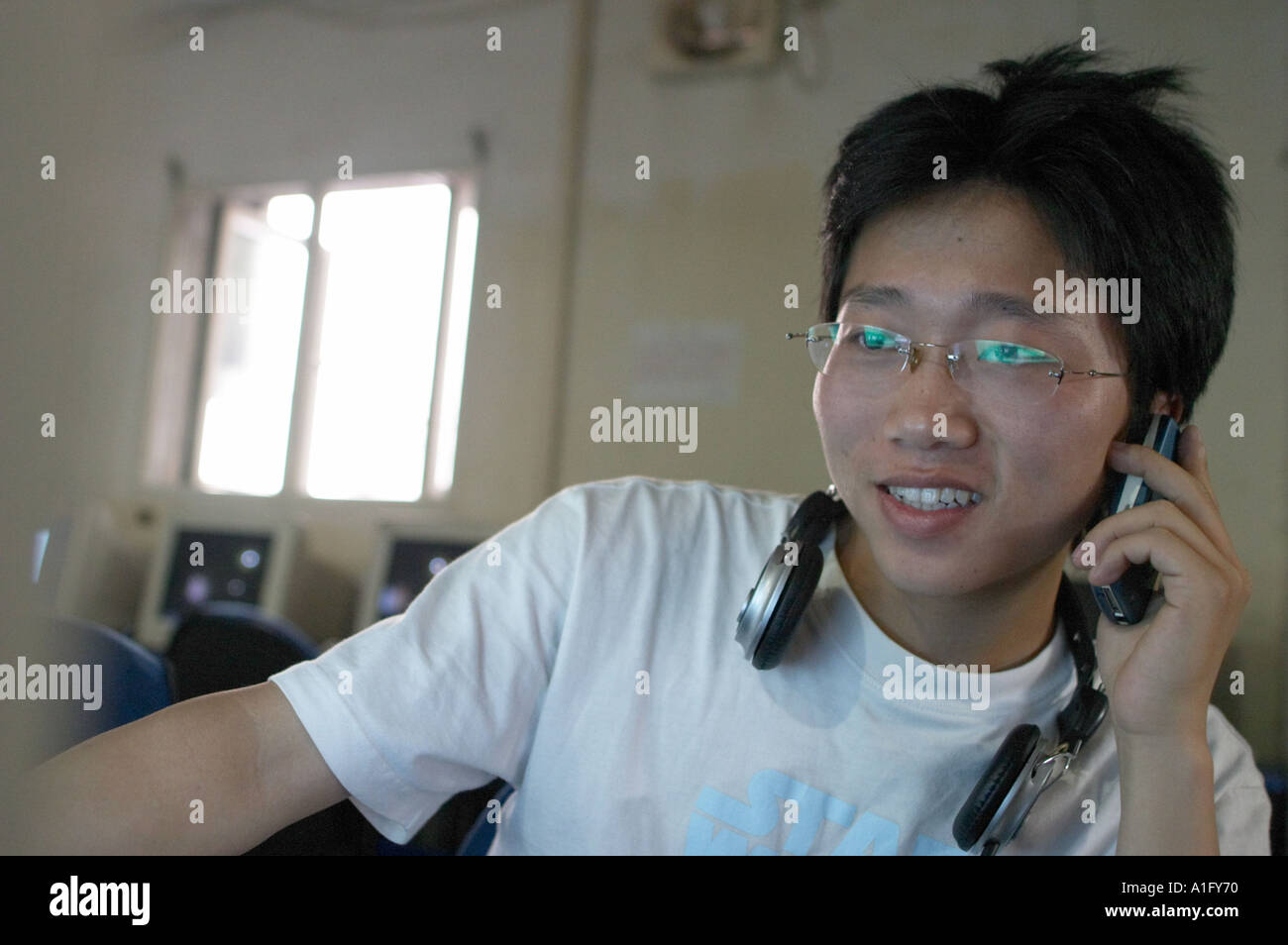 man talking on mobile phone whist using computer in internet cafe ...