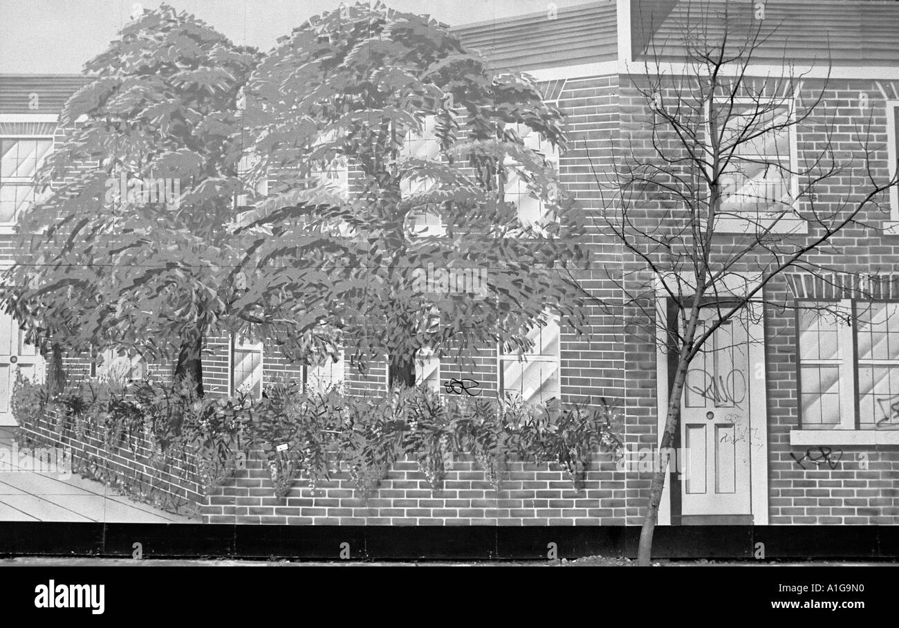 A stunted sapling grows next to idealized trees on a hording painted ...