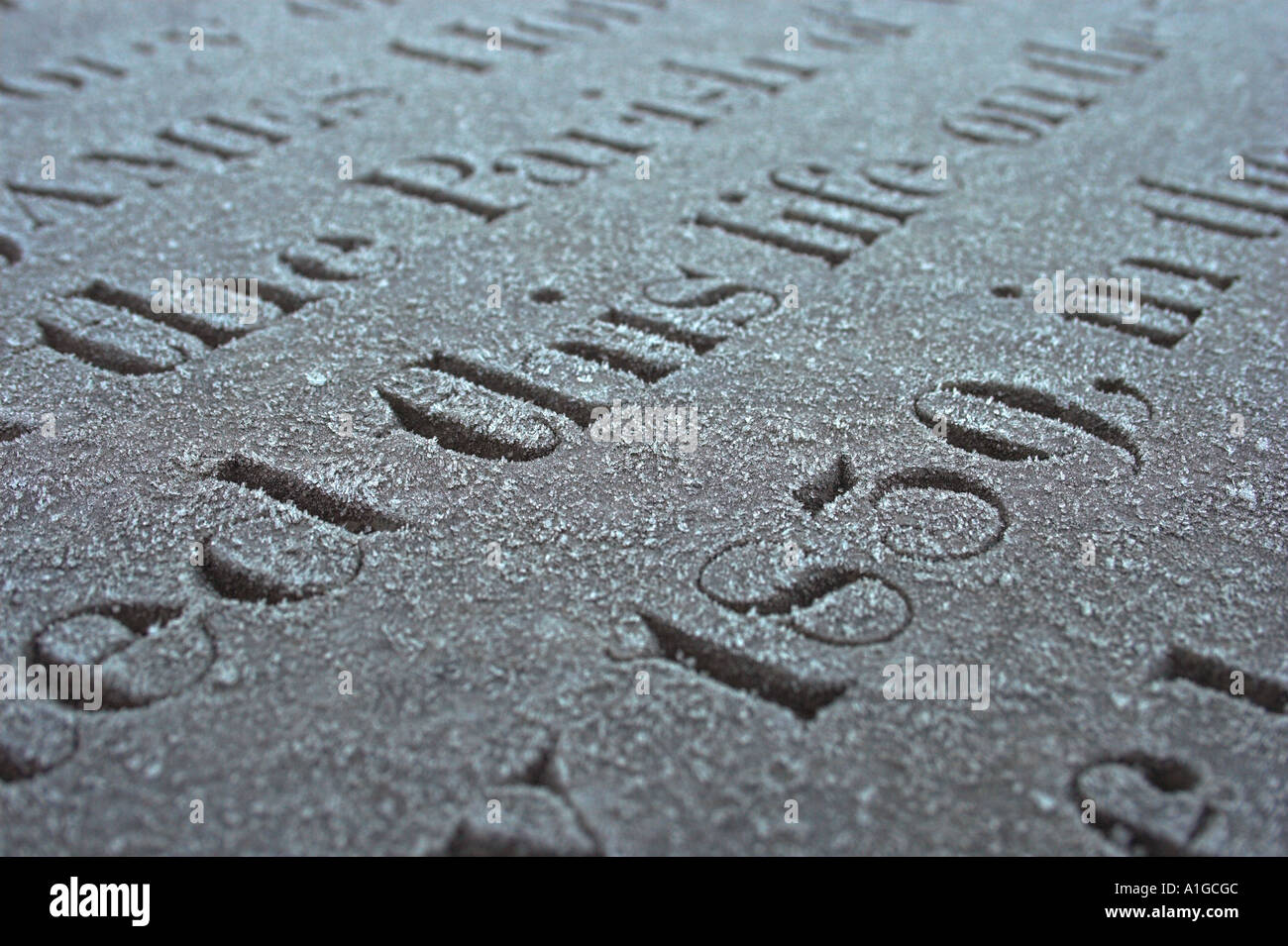 damaged and weathered and worn engraving on a frosty tombstone grave ...