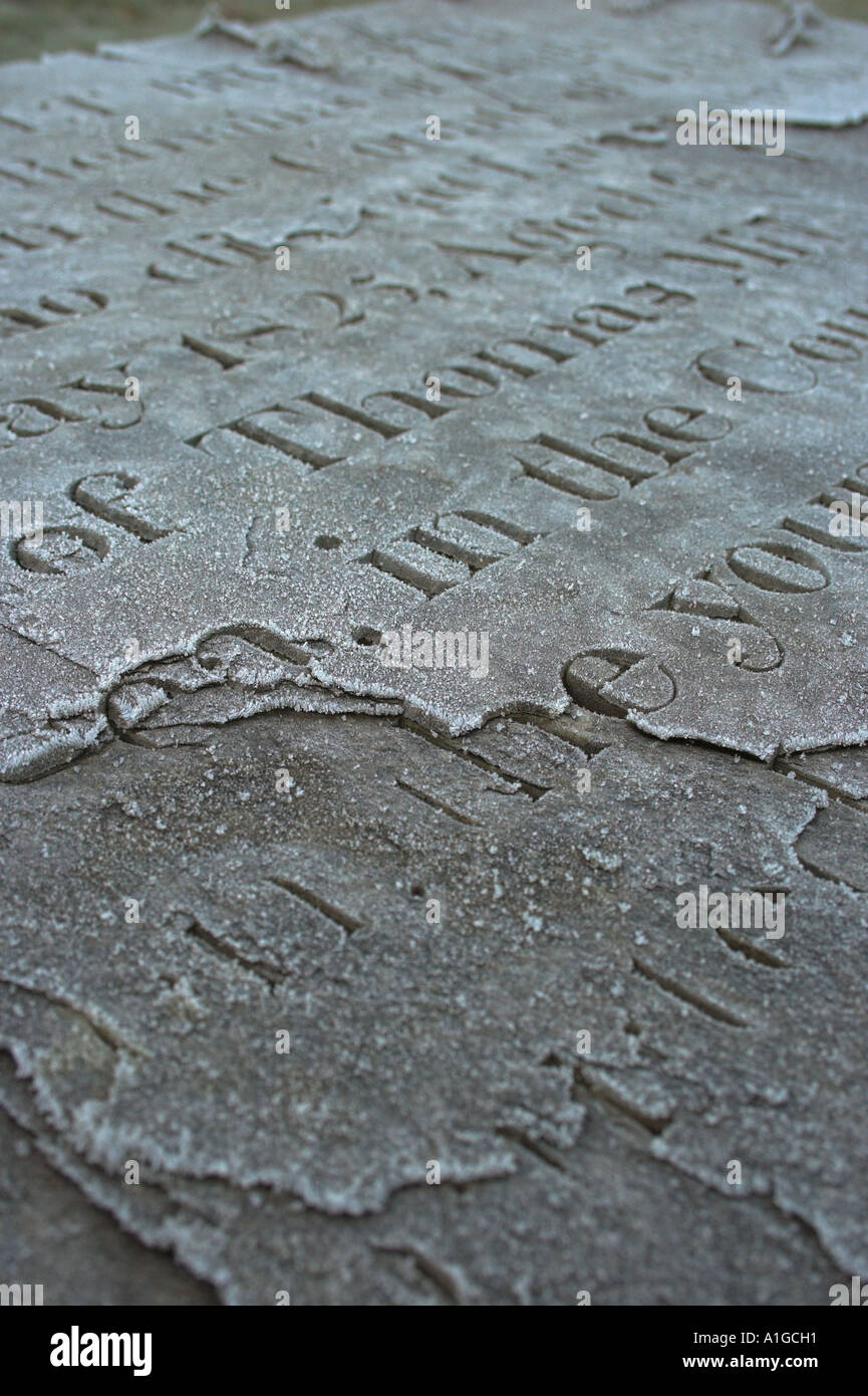 damaged and weathered and worn engraving on a frosty tombstone grave ...