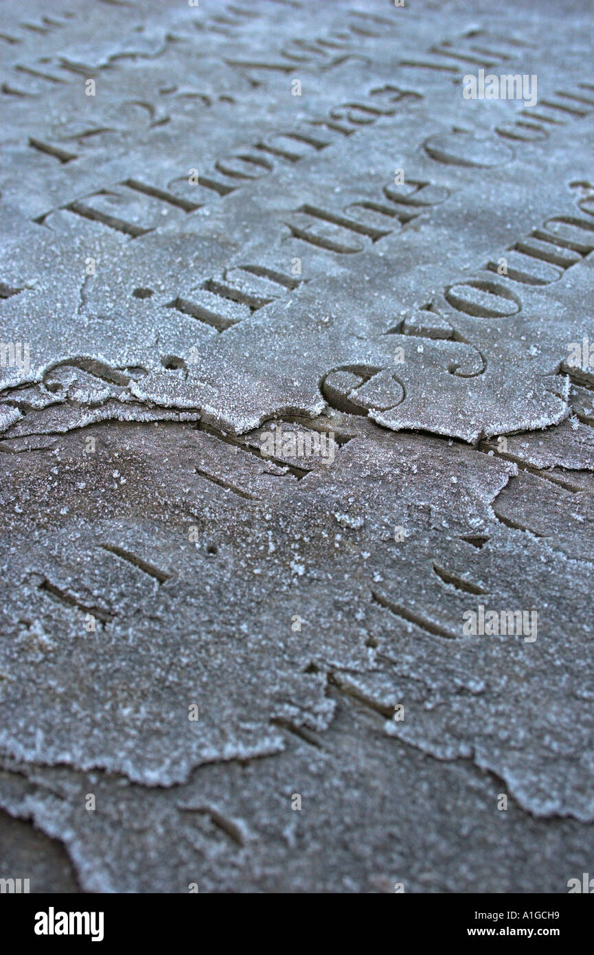 damaged and weathered and worn engraving on a frosty tombstone grave ...