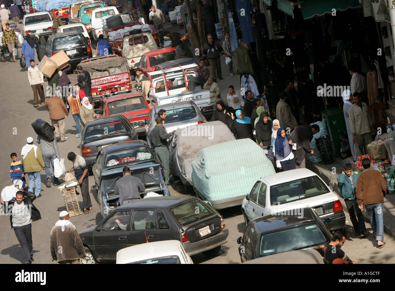 Street scene from central Cairo. Cars and people carrying goods mix ...