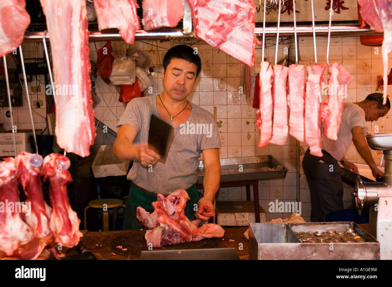 Stock photograph of a butcher cutting a pigs head in a street market on ...