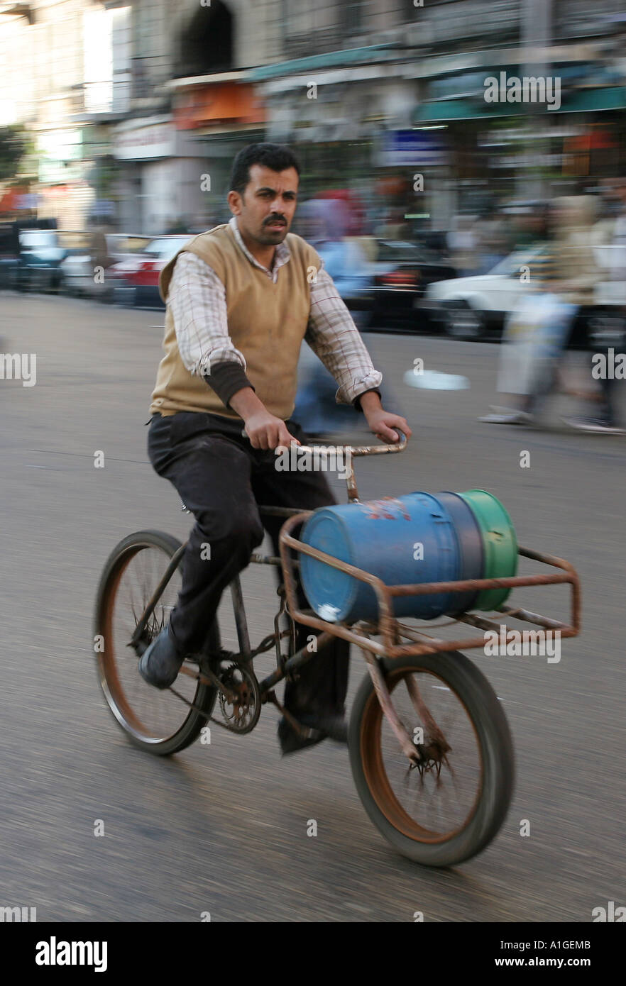 A man carrying a bucket rides past on his bicycle in central Cairo ...