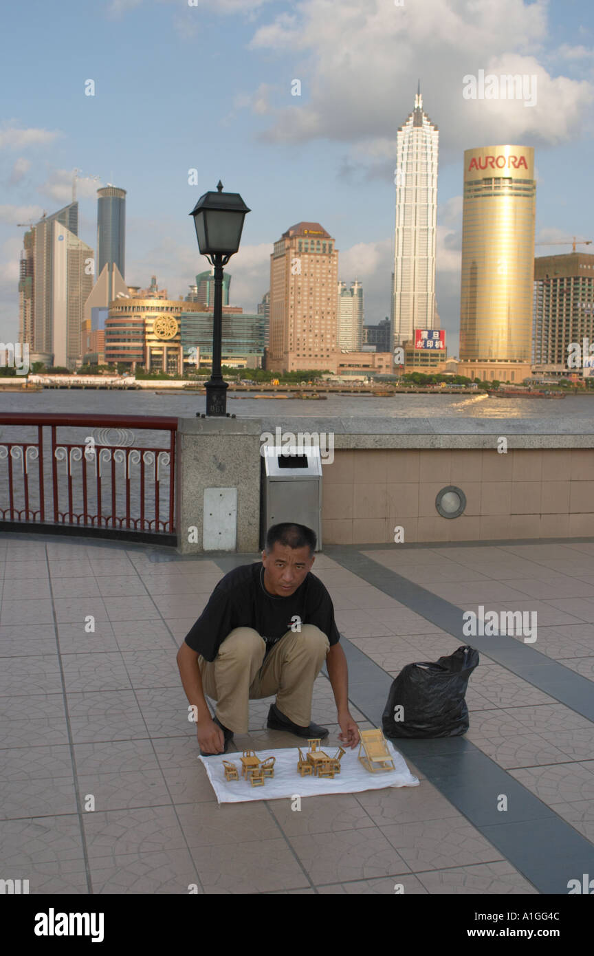 chinese man selling tourist trinkets on the bund with a view of pudong ...