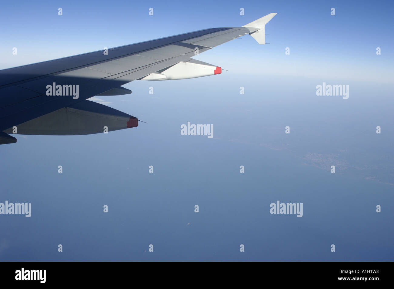 Window view of aircraft wingtip in flight over the English Channel in ...