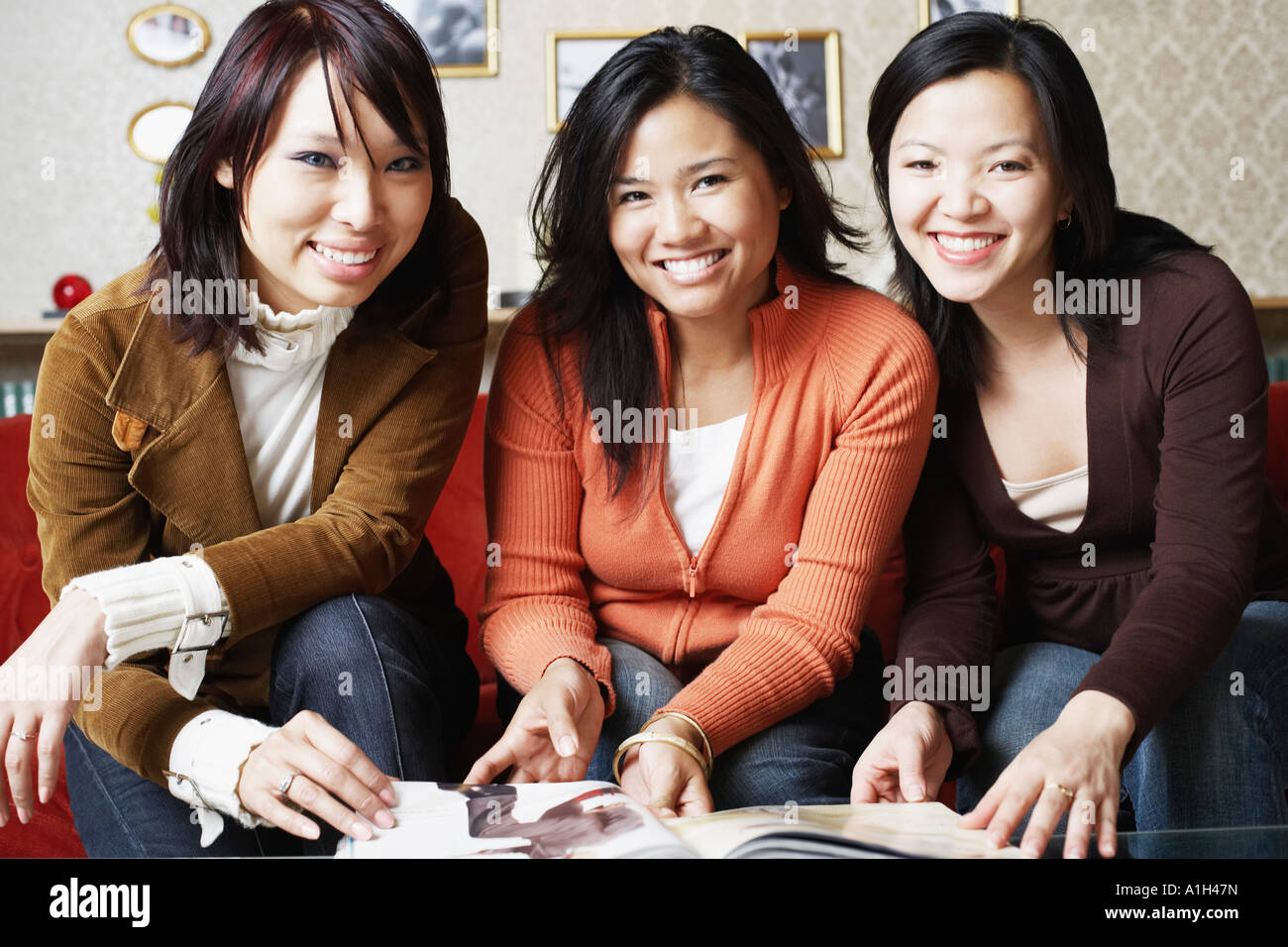 Portrait of three young women sitting together smiling Stock Photo - Alamy