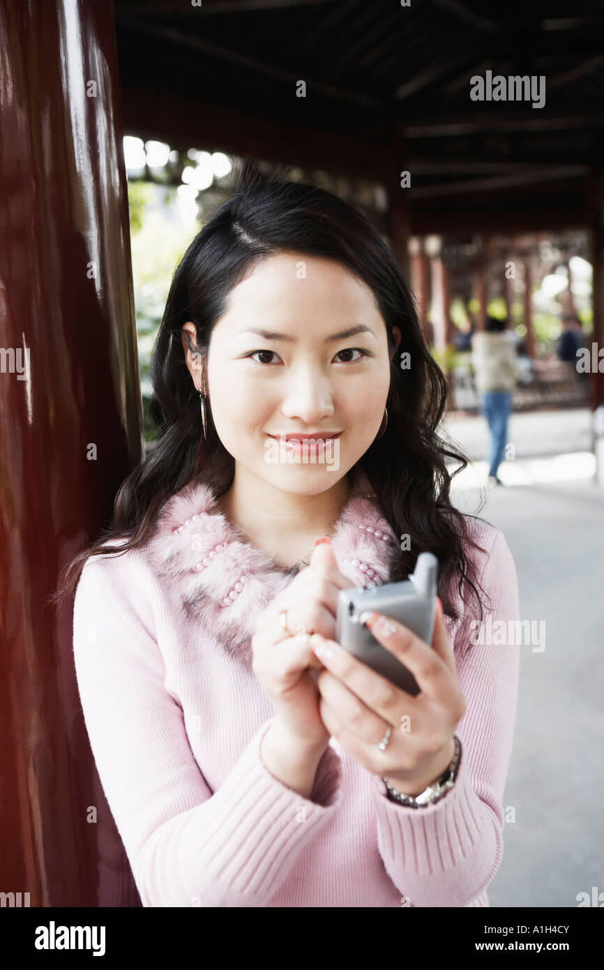 Portrait of a young woman operating a mobile phone with a digitized pen ...
