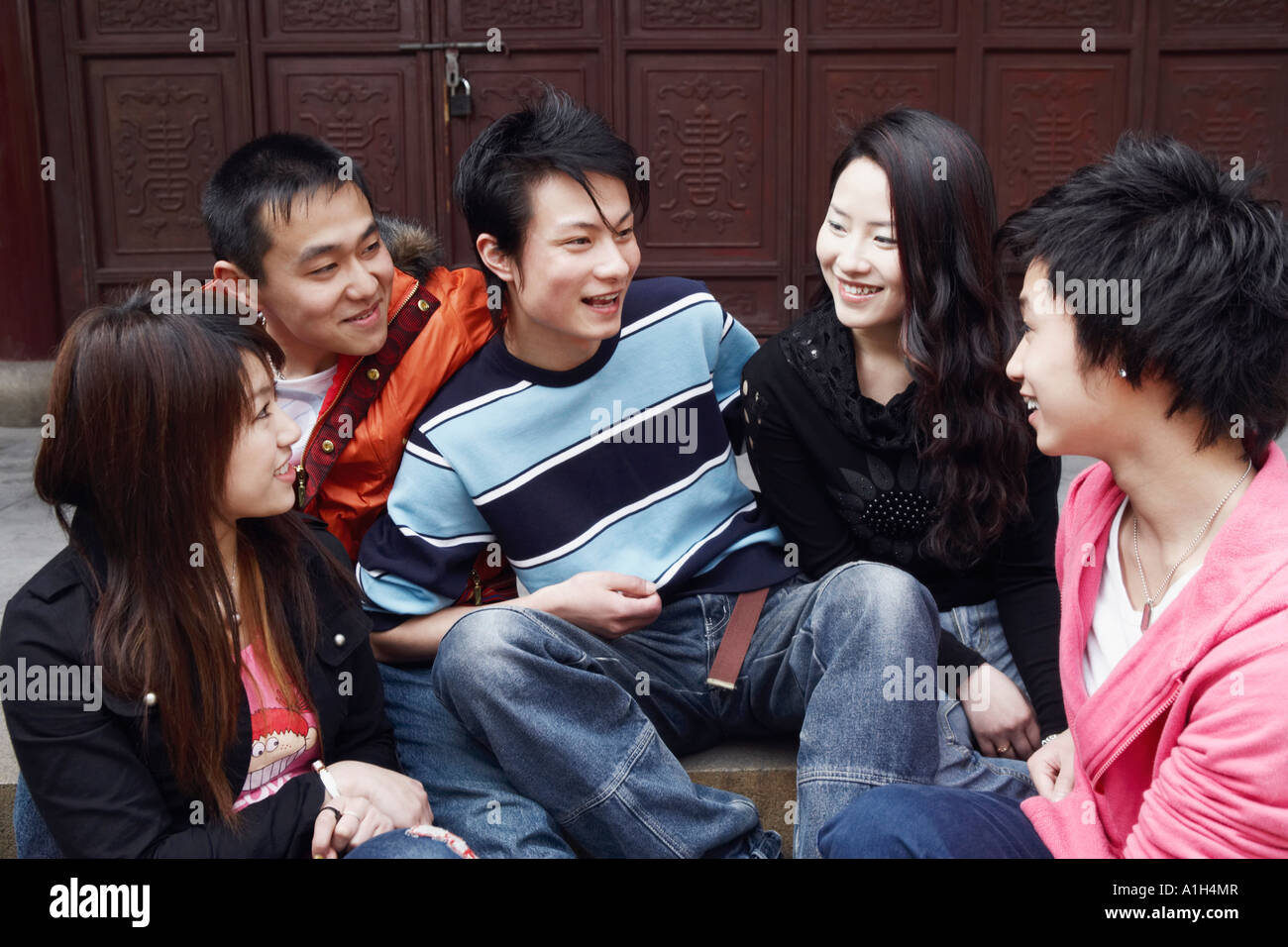 Two young men talking to two young women and a teenage boy Stock Photo ...
