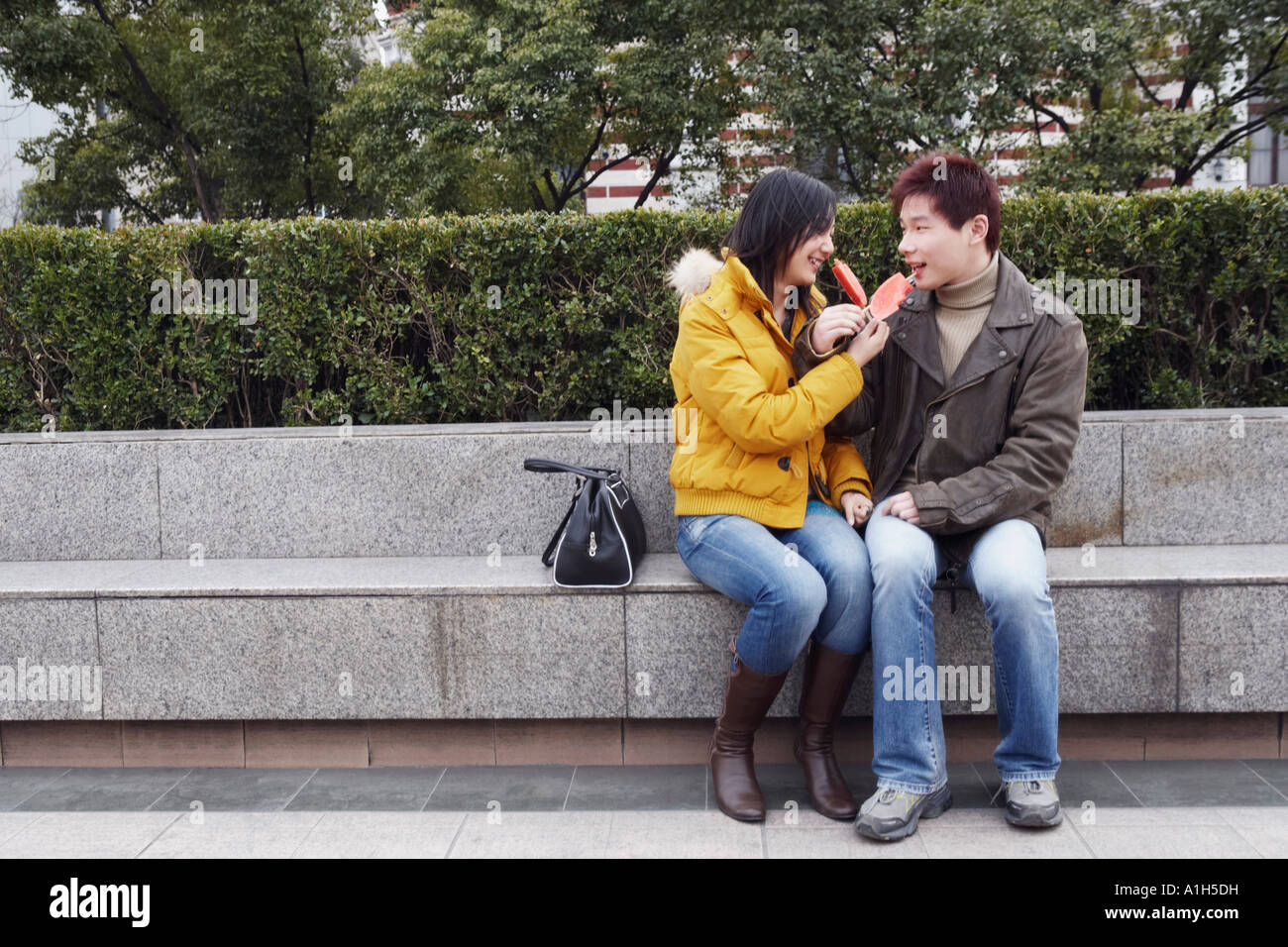 Young couple sitting on the ledge eating watermelon Stock Photo - Alamy