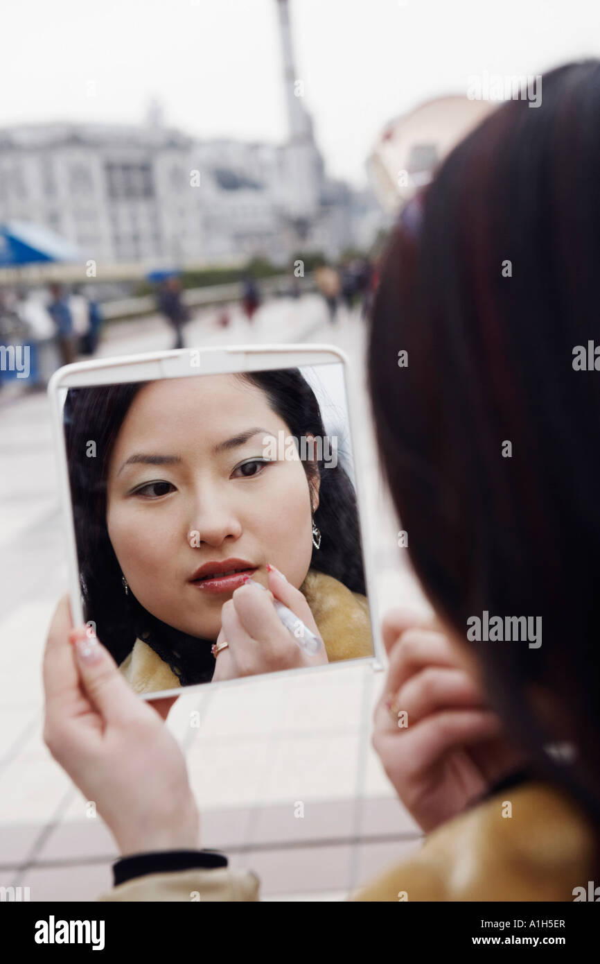 Close-up of a young woman looking into a mirror applying lipstick Stock ...