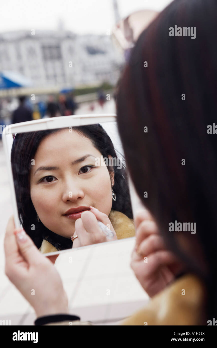Close-up of a young woman looking into a mirror applying lipstick Stock ...