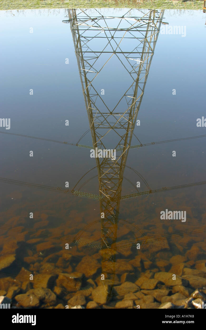 Electricity supply line pylon reflected in glass calm water Stock Photo ...