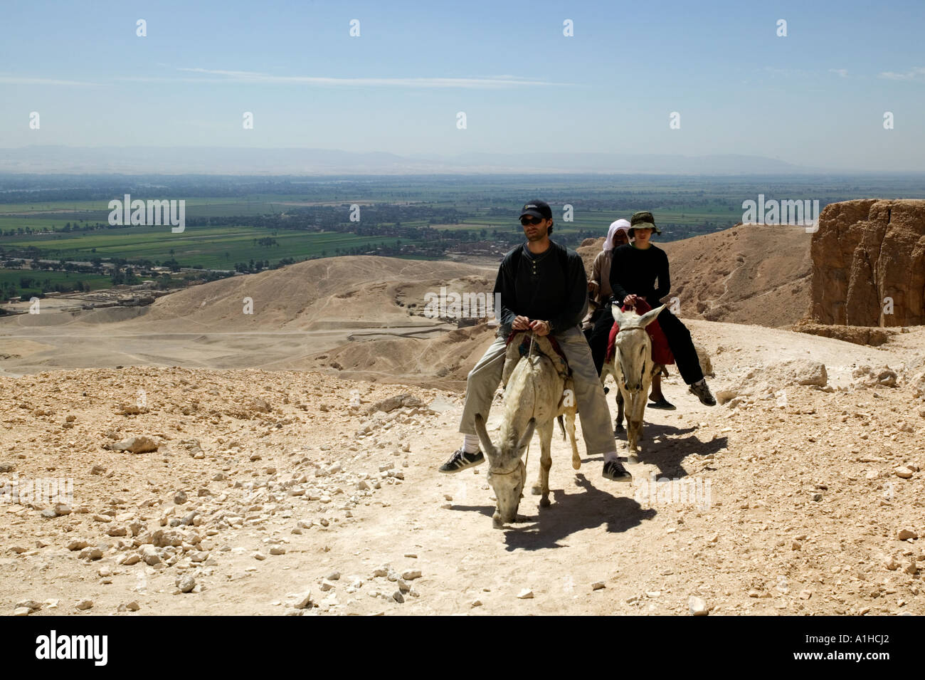 Tourists riding donkeys on top of a mountain in the Valley of the Kings ...