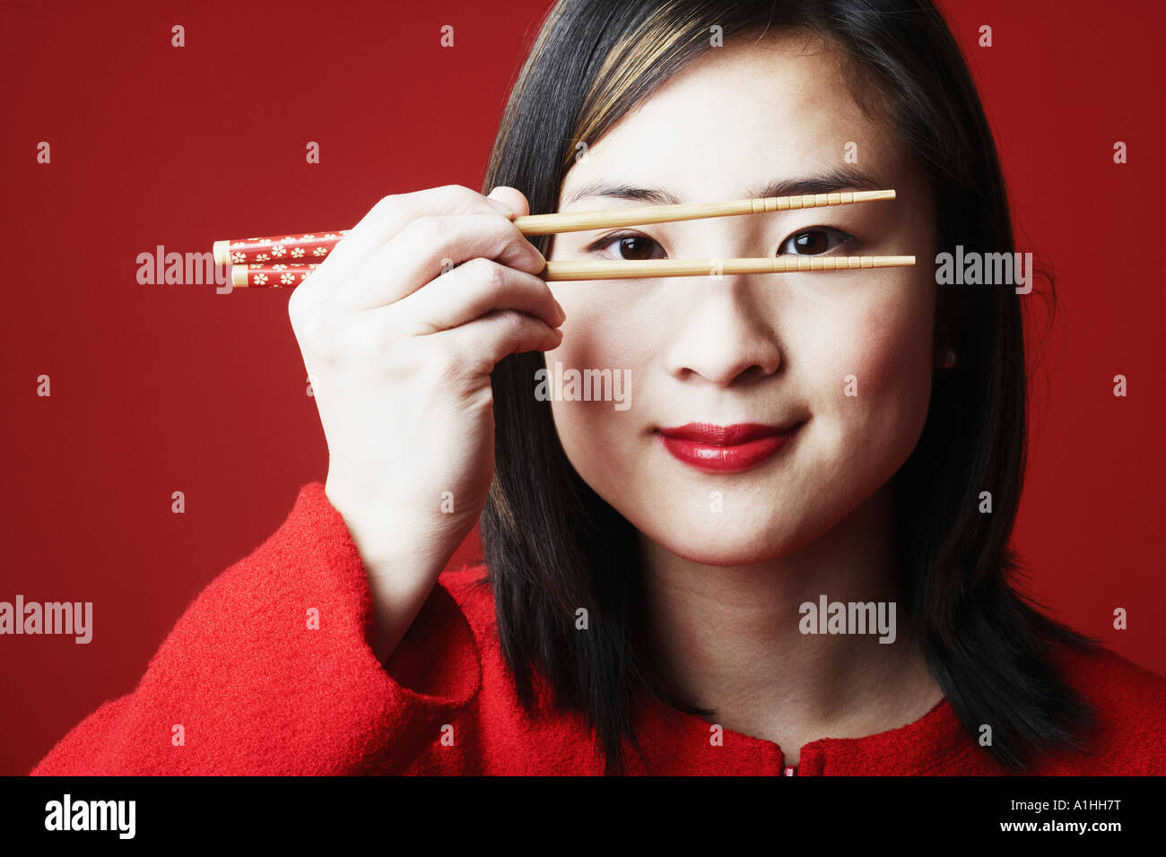 Portrait of a young woman looking through chopsticks Stock Photo - Alamy