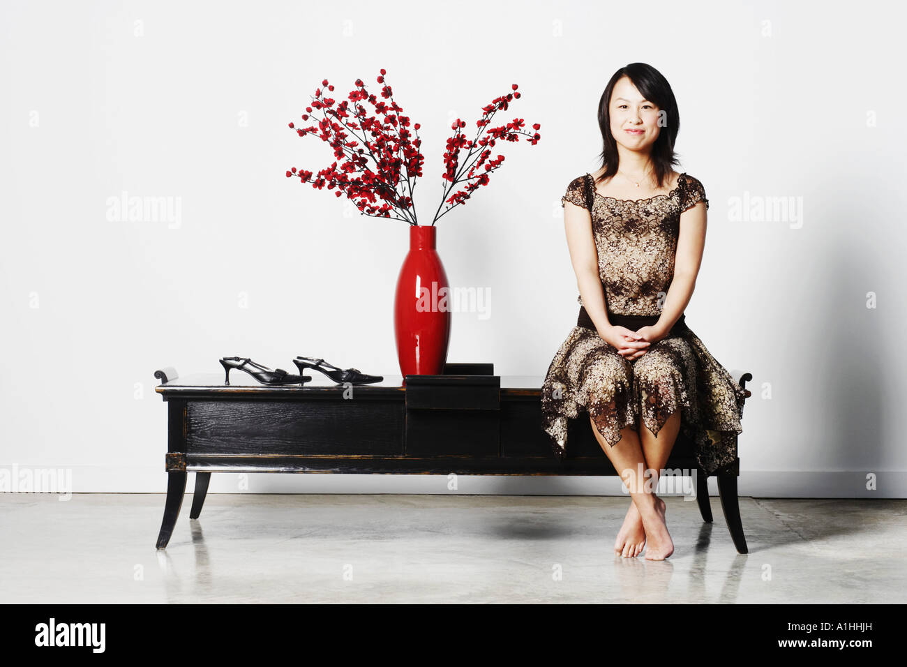 Portrait of a young woman sitting on a table Stock Photo - Alamy
