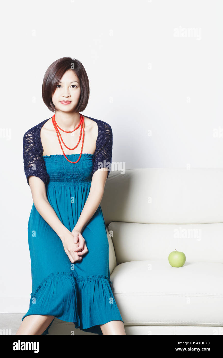 Portrait of a young woman sitting on the arm of an arm chair Stock ...