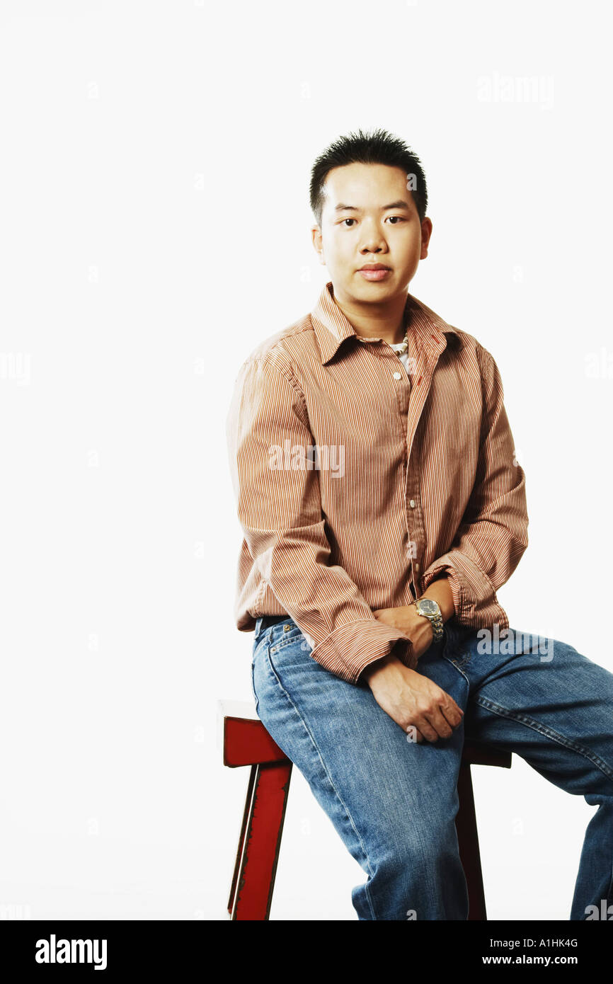 Portrait of a young man sitting on a stool Stock Photo - Alamy