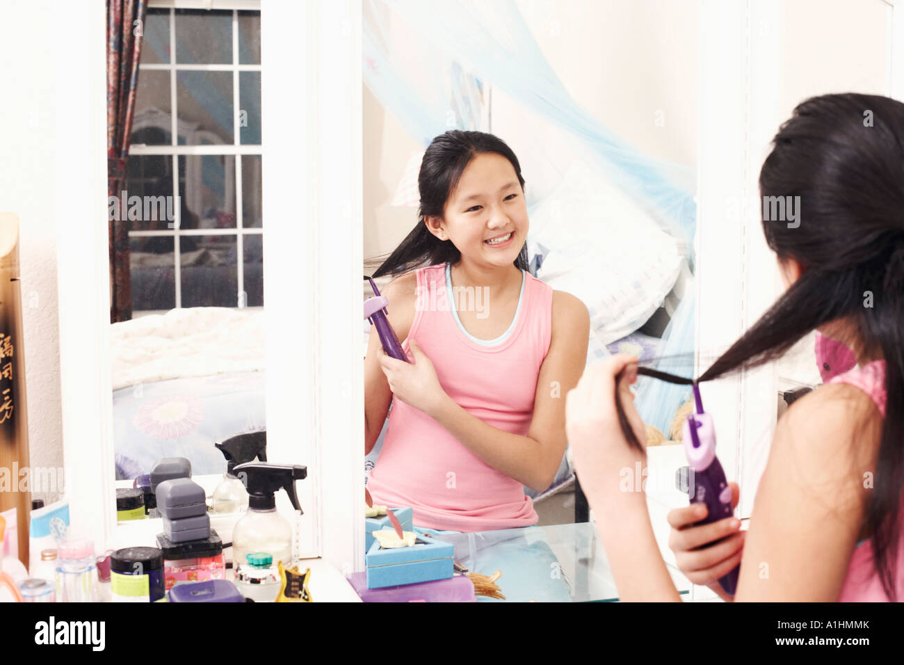 Girl styling her hair in the mirror Stock Photo - Alamy