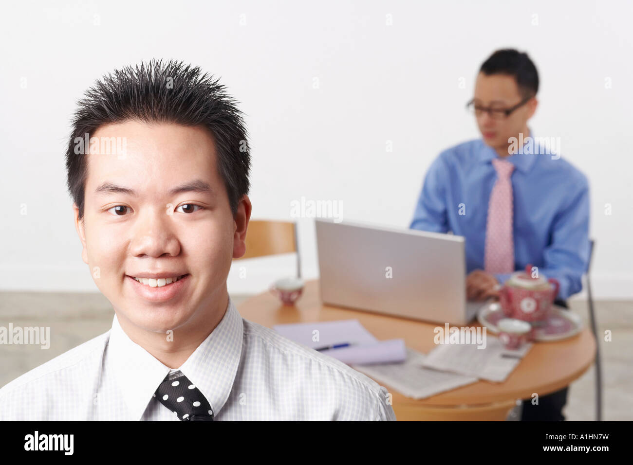 Portrait of a businessman smiling with another businessman using a ...