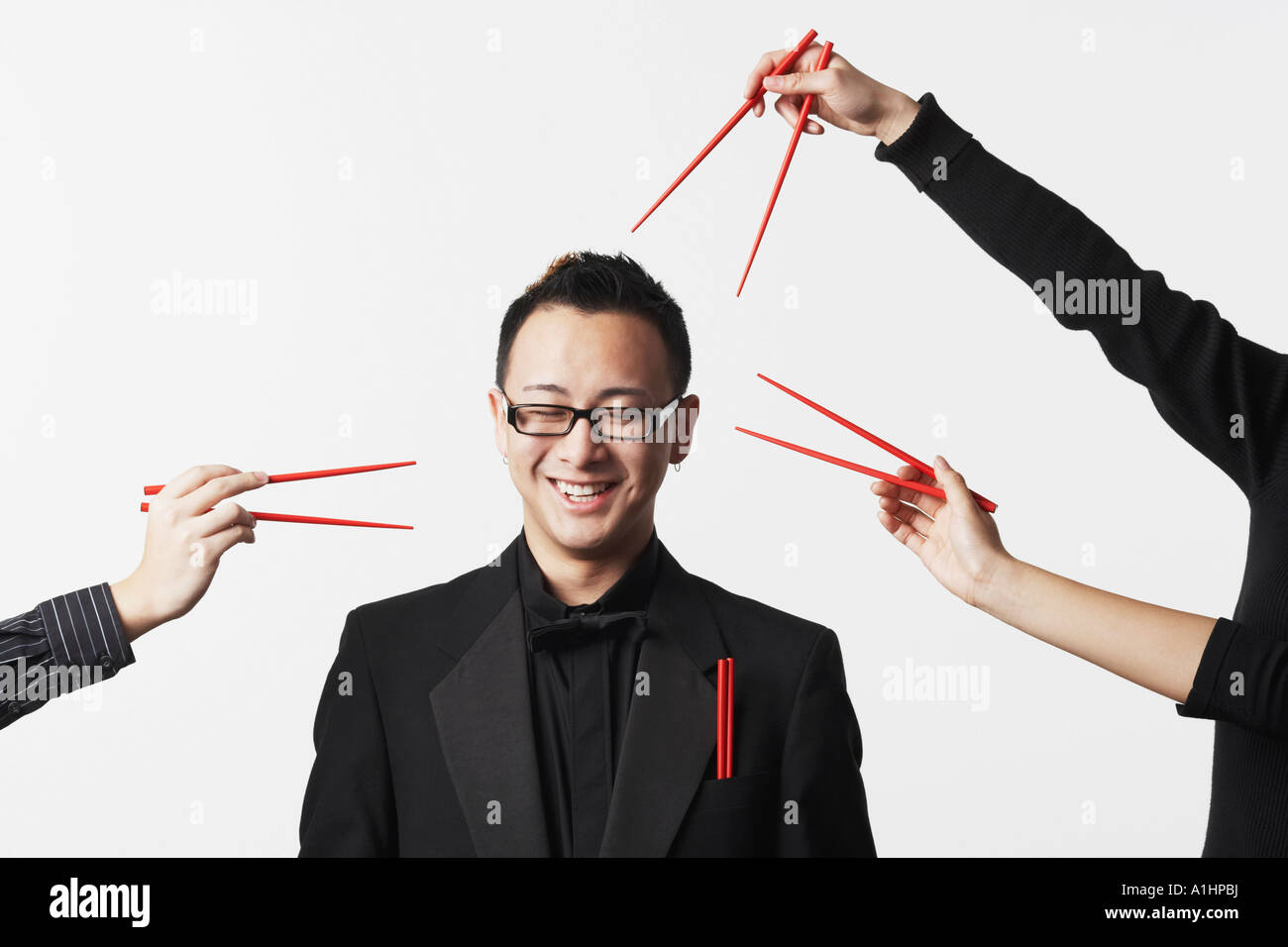 Three people holding chopsticks around a businessman Stock Photo - Alamy