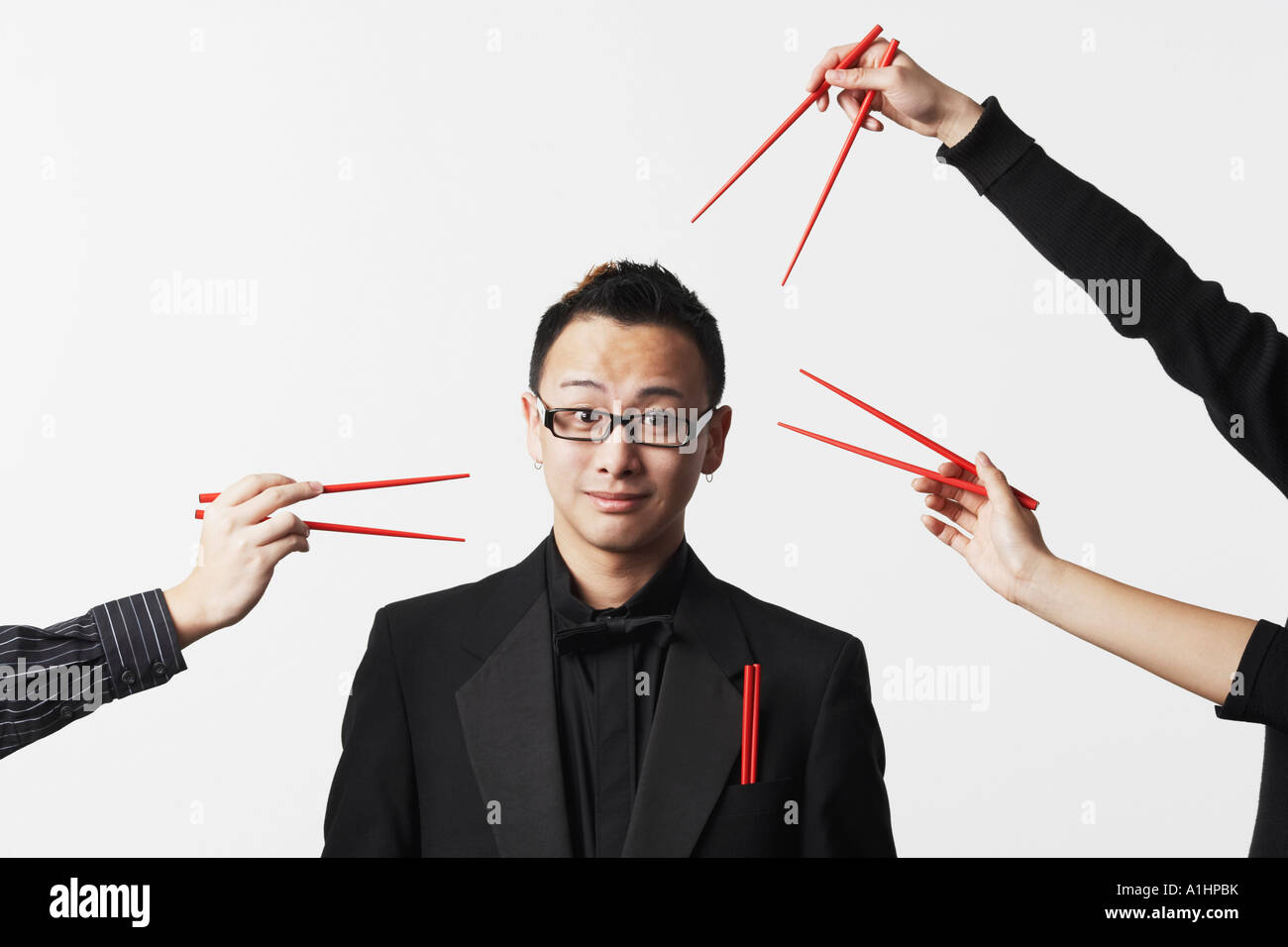 Three people holding chopsticks around a businessman Stock Photo - Alamy