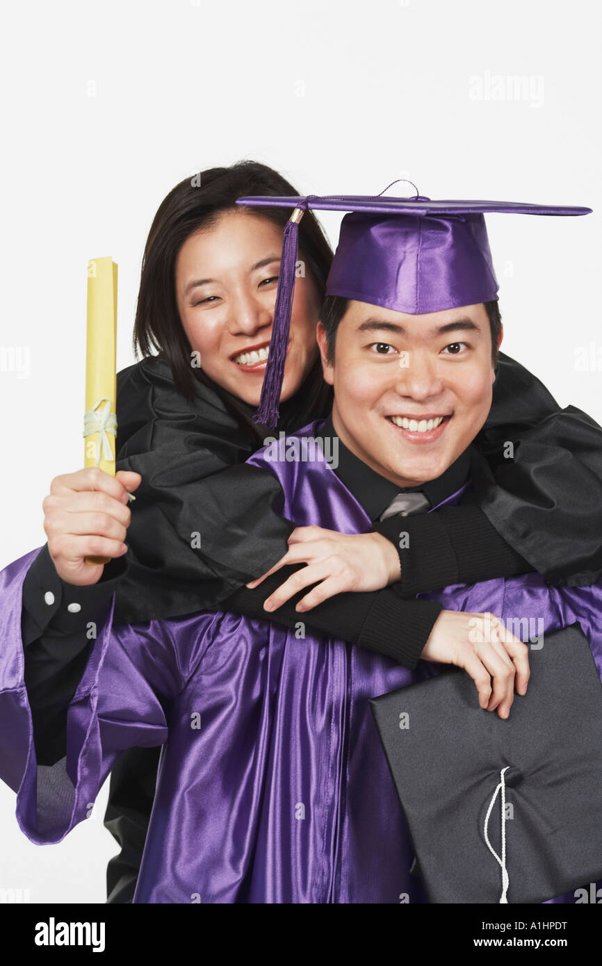 Portrait of a young woman riding piggyback on a male graduate Stock ...