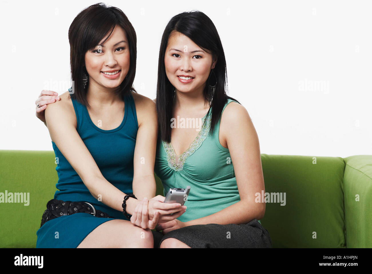 Portrait of two young women holding a mobile phone Stock Photo - Alamy