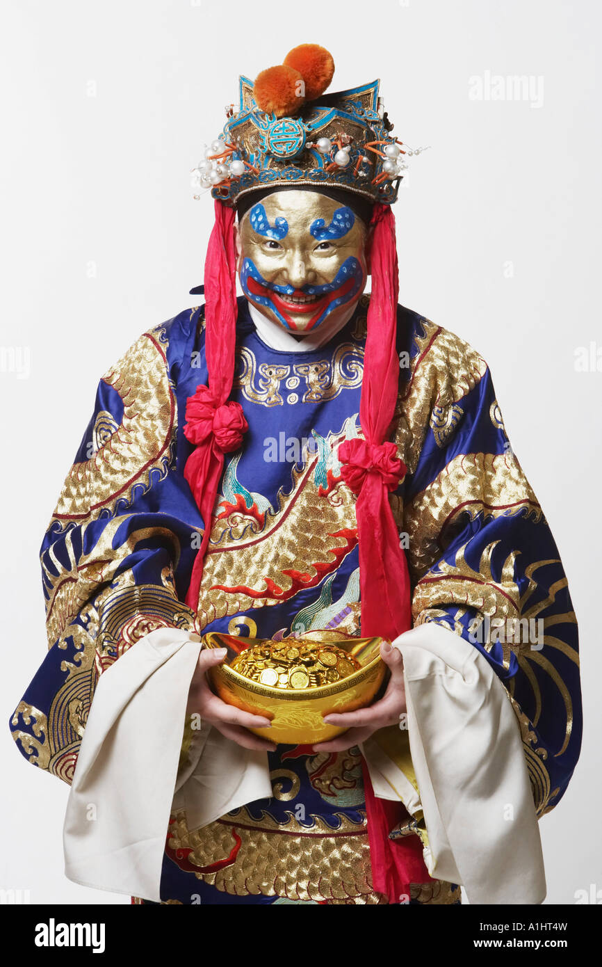 Portrait of a male Chinese opera performer holding a bowl full of gold ...
