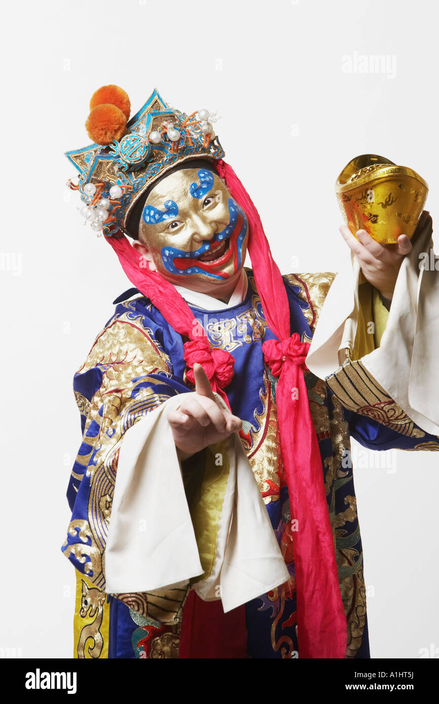 Portrait of a male Chinese opera performer holding a bowl full of gold ...