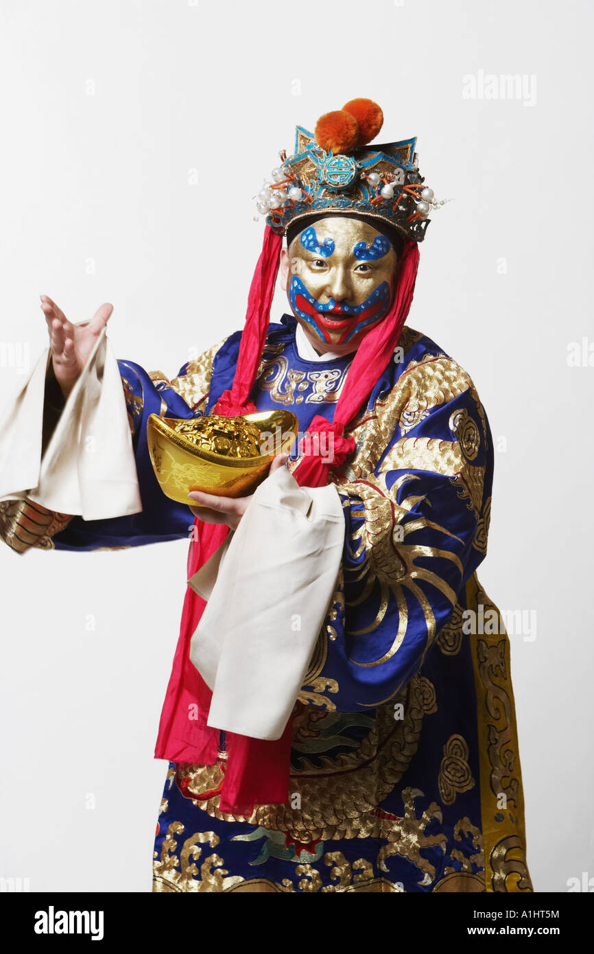 Portrait of a male Chinese opera performer holding a bowl full of gold ...
