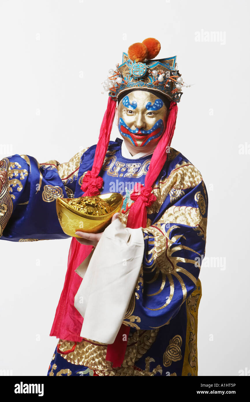 Close-up of a male Chinese opera performer holding a bowl full of gold ...