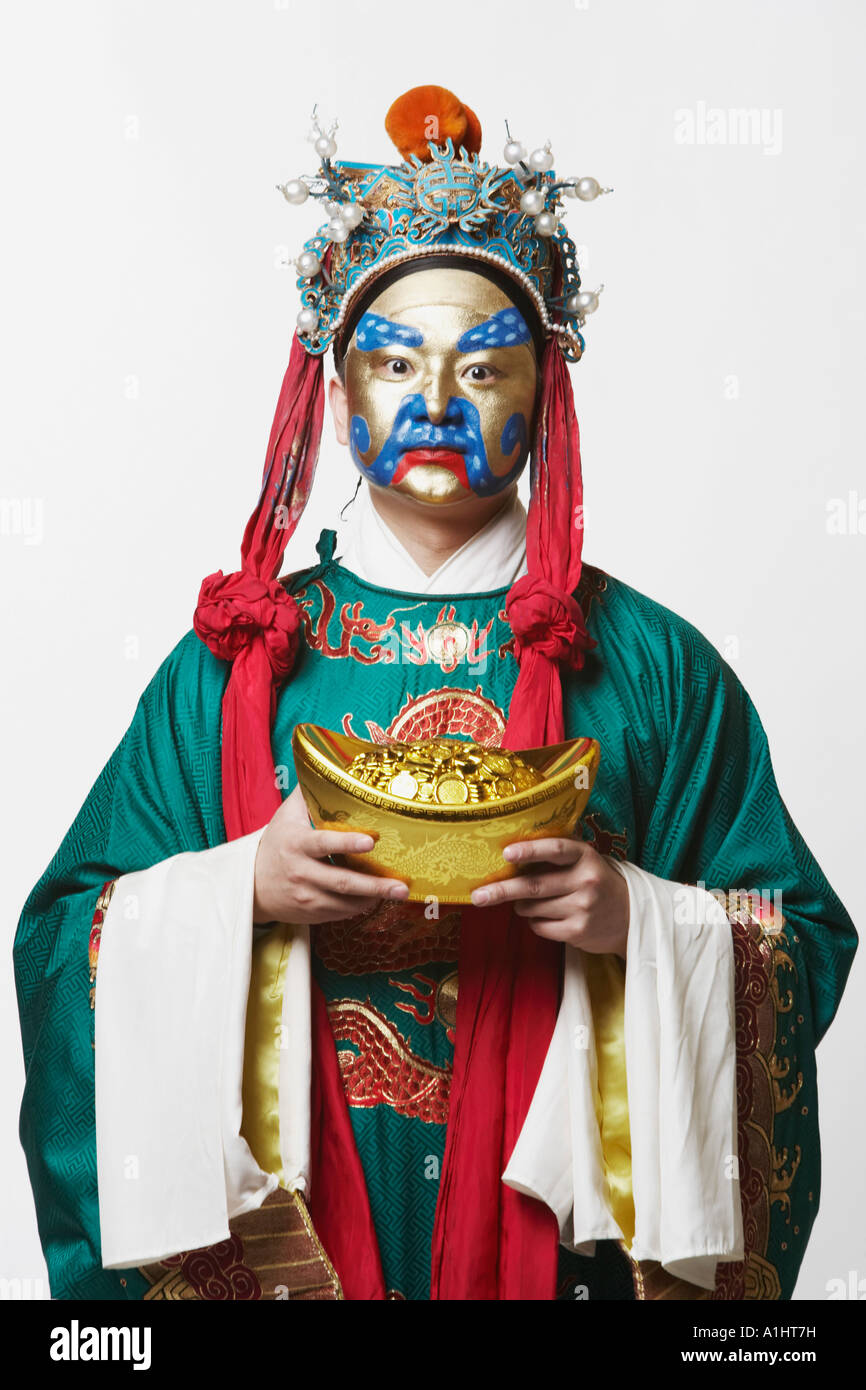 Portrait of a male Chinese opera performer holding a bowl full of gold ...