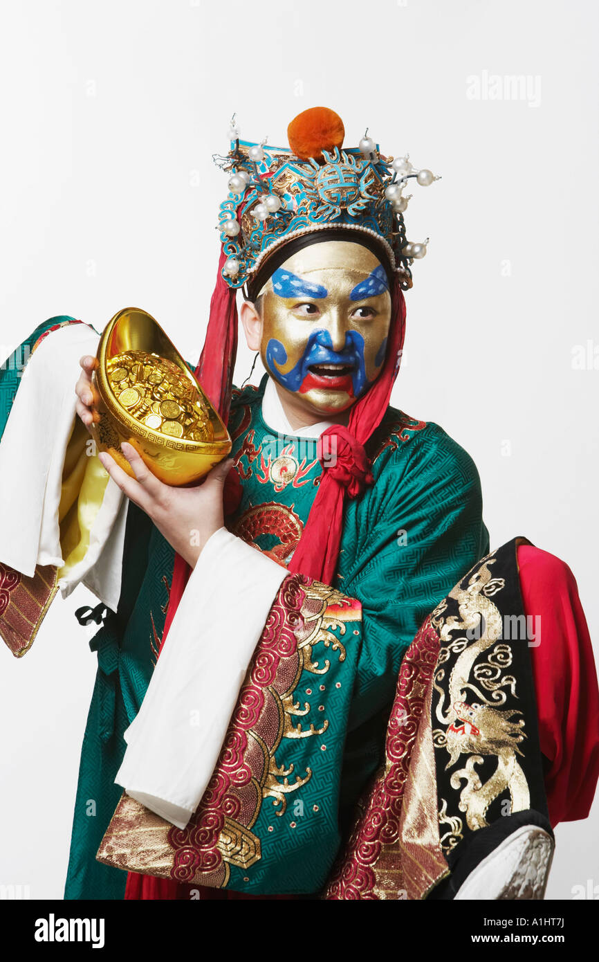 Close-up of a male Chinese opera performer holding a bowl full of gold ...