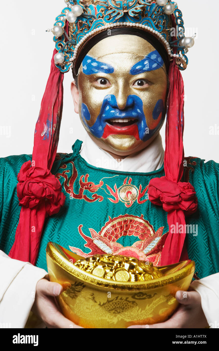 Portrait of a male Chinese opera performer holding a bowl full of gold ...