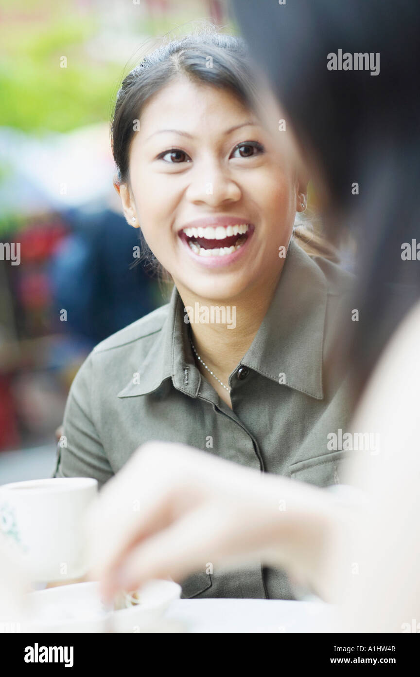 Young woman talking to another woman and laughing Stock Photo - Alamy
