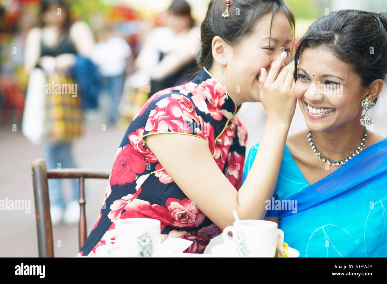 Close-up of a young woman whispering into another woman's ear Stock ...