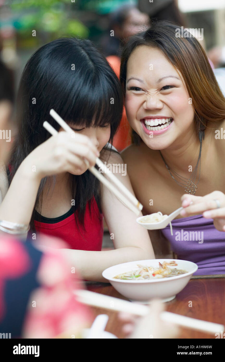 Close-up of two young women eating noodles with chopsticks Stock Photo ...