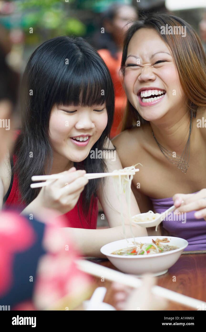 Close-up of two young women eating noodles with chopsticks Stock Photo ...