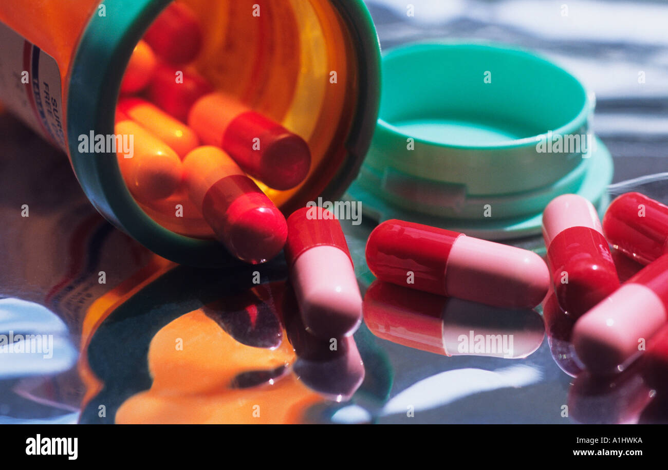 Capsules spilling from open container. Prescription medication. Drugs ...