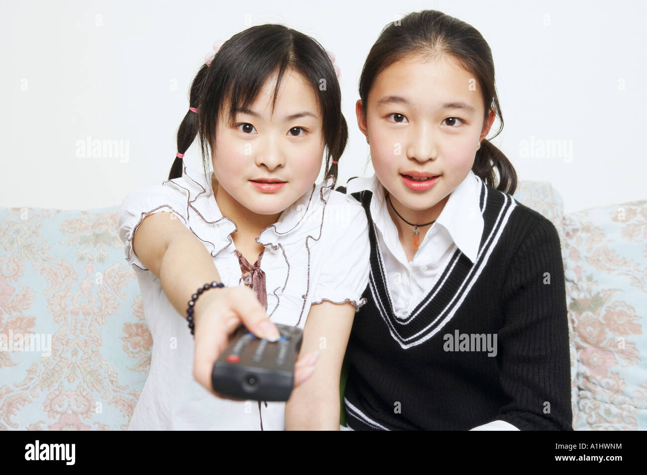 Portrait of a young woman sitting together with her sister holding a ...