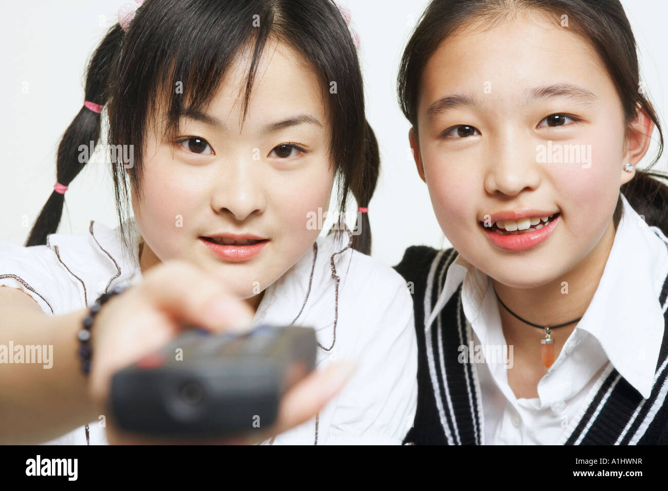 Portrait of a young woman with her sister holding a remote control ...