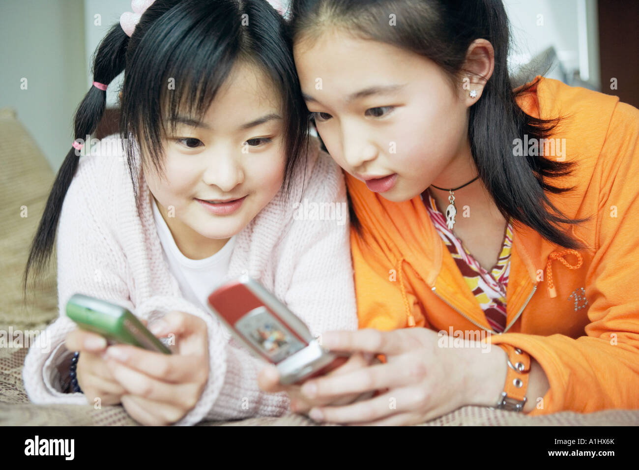 Close-up of two sisters using mobile phones Stock Photo - Alamy